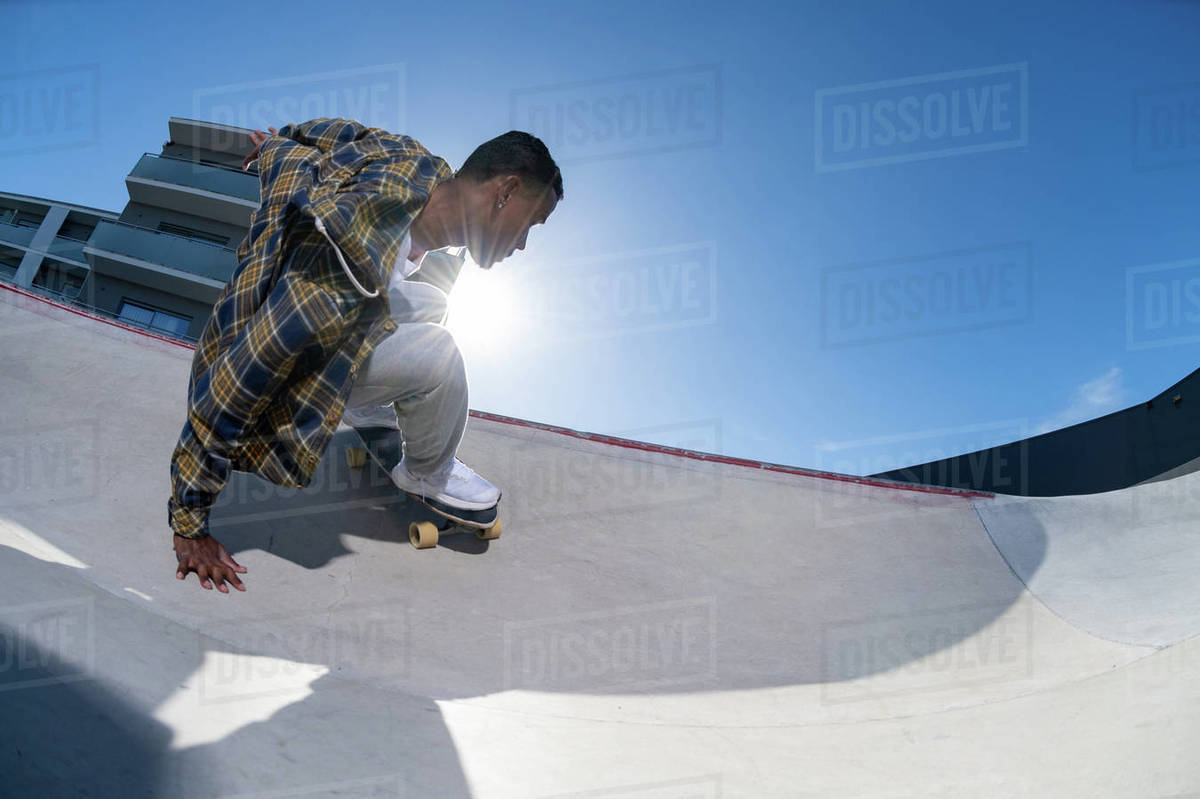 Surf skater performing a slide on a skatepark during a sunny day ...
