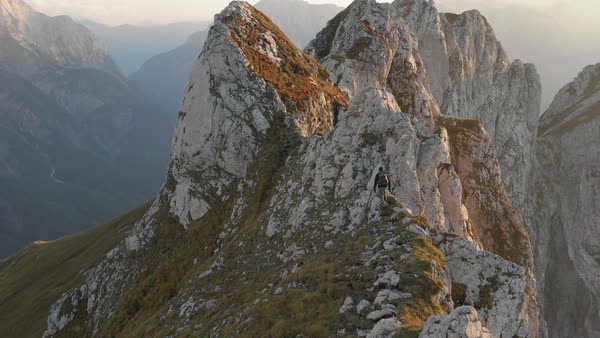 Man hiking up steep mountain on the ridge to to the top with steep ...