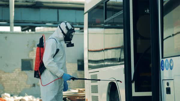 A person in a hazmat suit is spraying chemicals onto the bus - 4K ...
