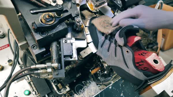 Factory worker using a shoe making machine at a footwear facility ...