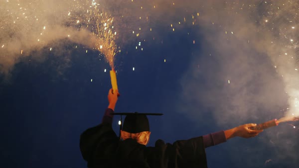 An emotional college graduate in a mantle and a graduation cap with two ...