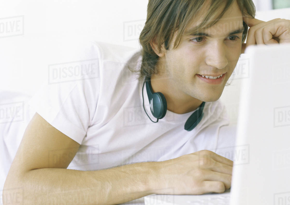 Man using laptop, headphones around neck - Royalty-free Stock Photo ...