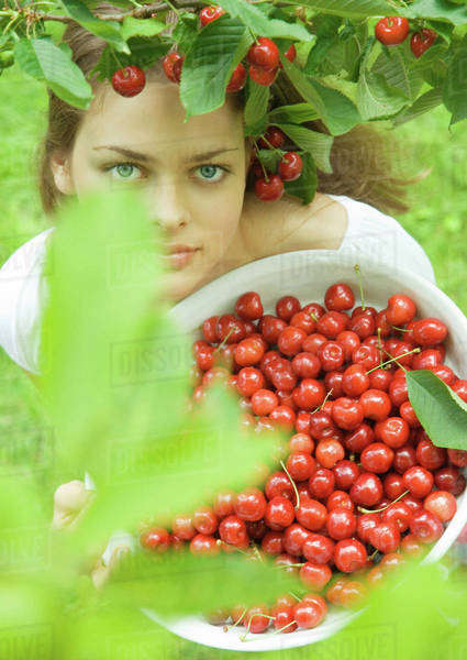 Woman holding bowl of cherries, standing under cherry tree - Royalty ...