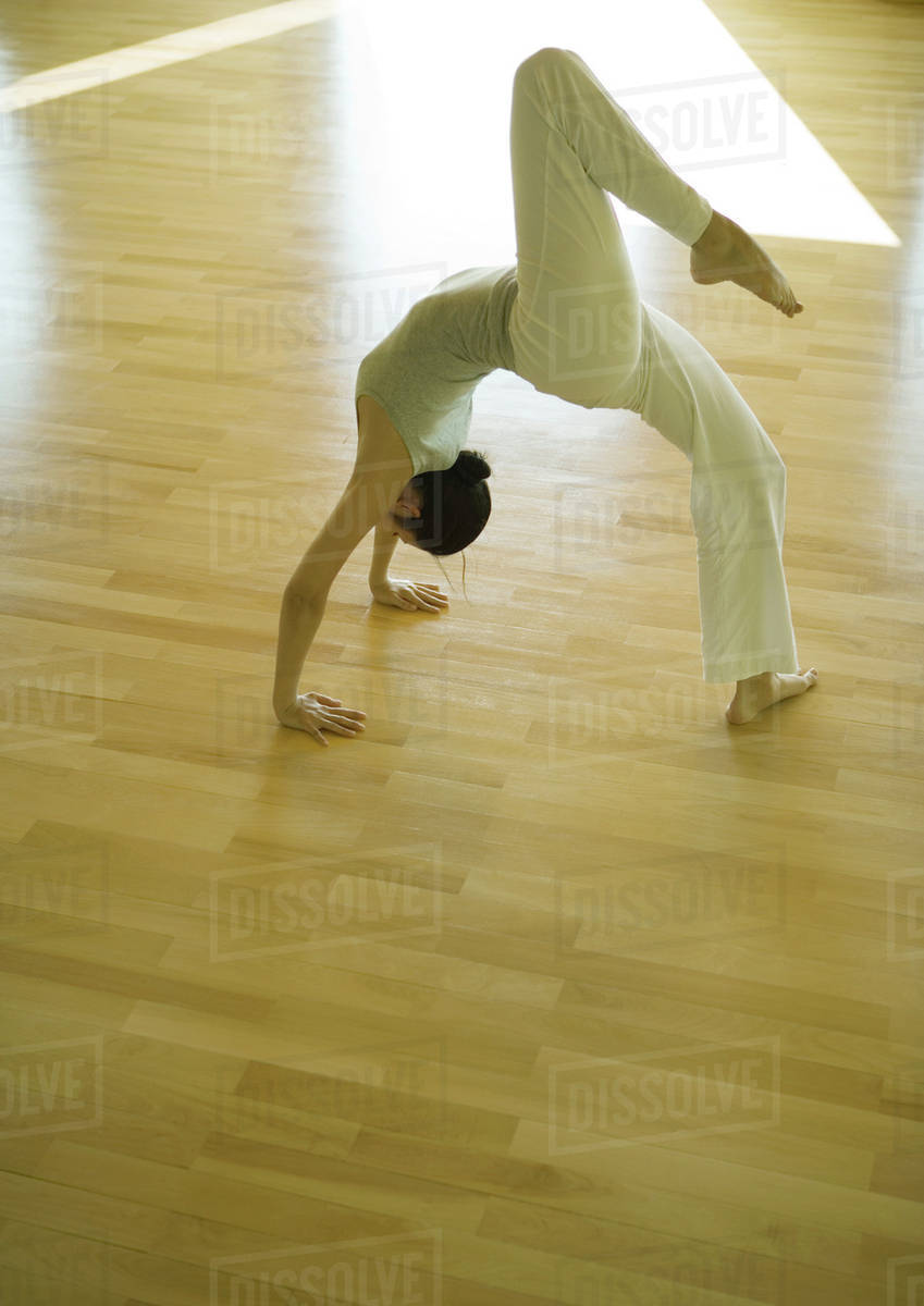 Yoga class, woman doing one-legged bridge pose - Stock Photo - Dissolve