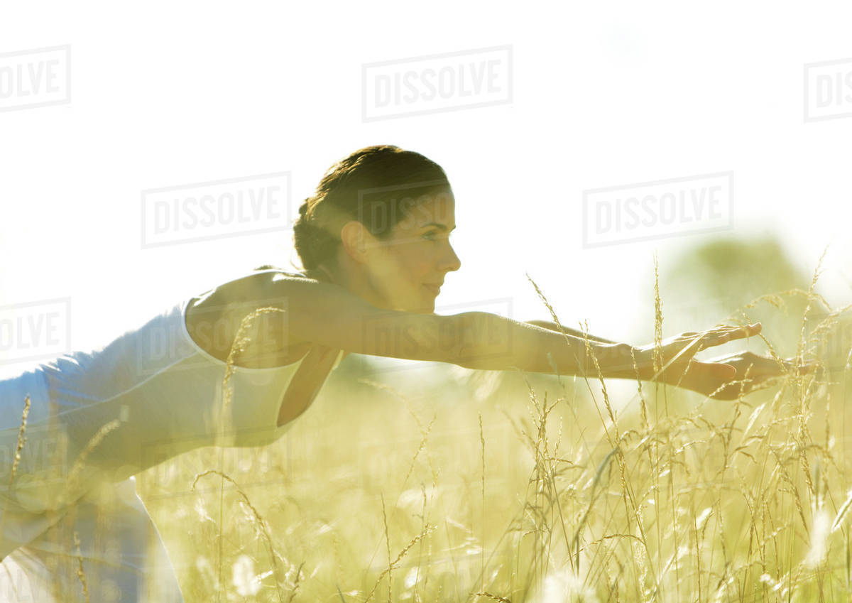 Woman stretching in field - Stock Photo - Dissolve