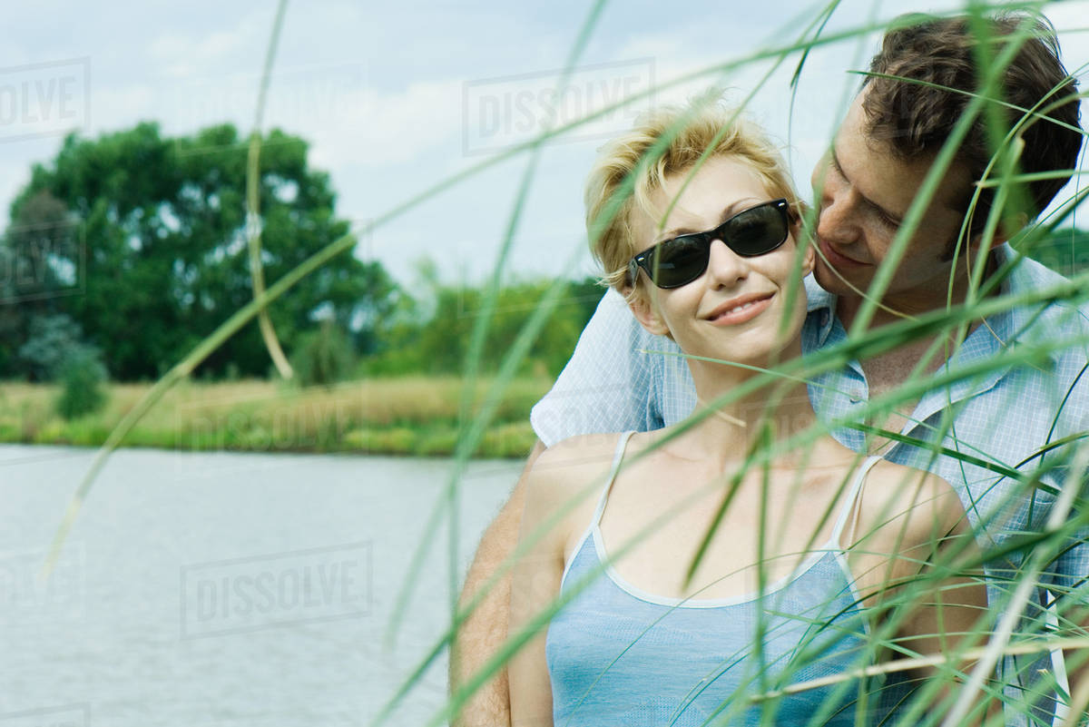 Couple, man looking over woman's shoulder, lake in background - Stock ...