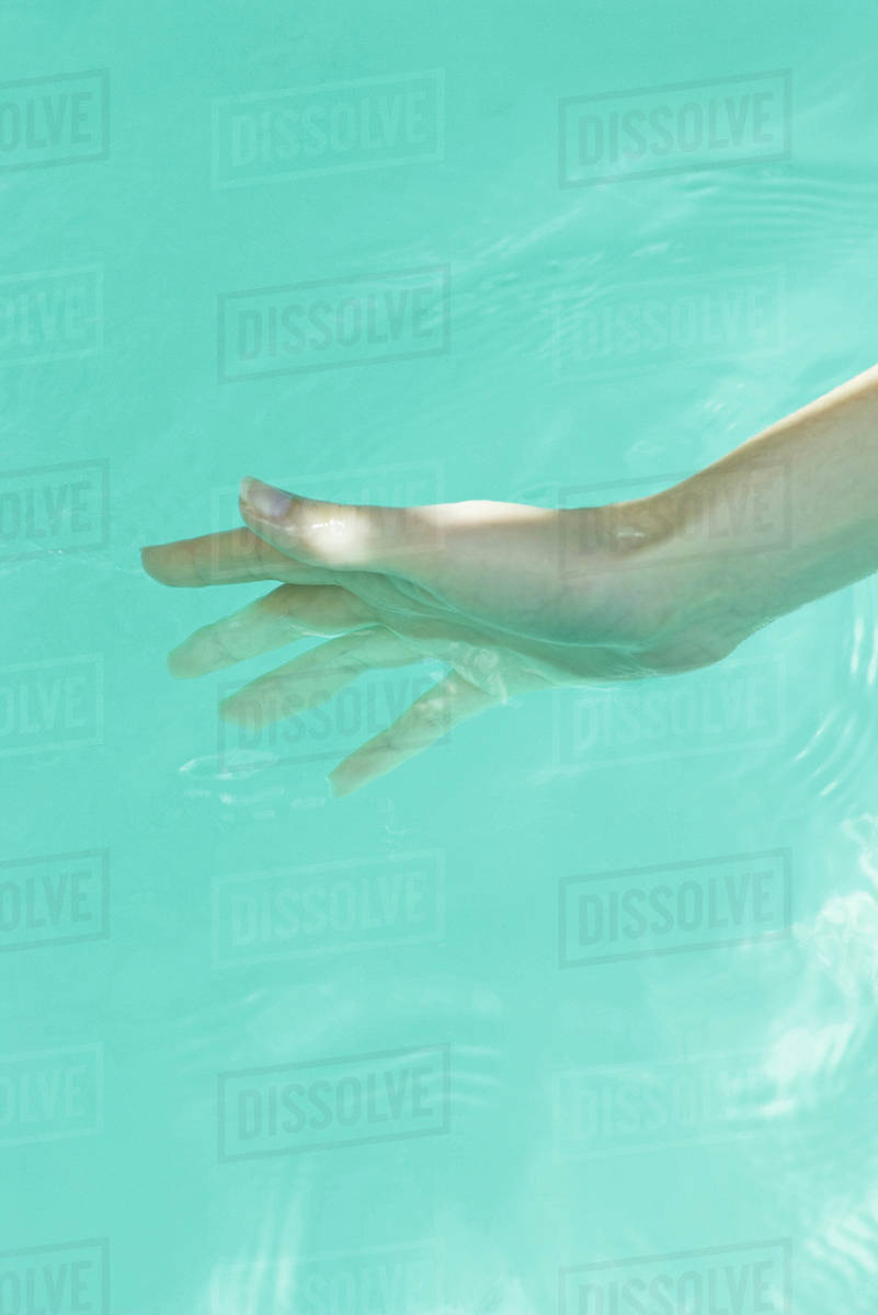 Young woman dipping hand into water, close-up - Stock Photo - Dissolve