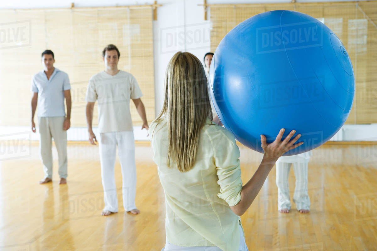 Group therapy, woman throwing ball to group - Stock Photo - Dissolve
