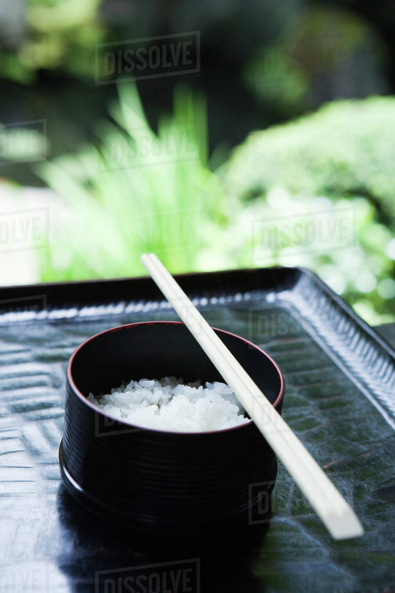 Chopsticks resting on bowl of white rice - Stock Photo - Dissolve