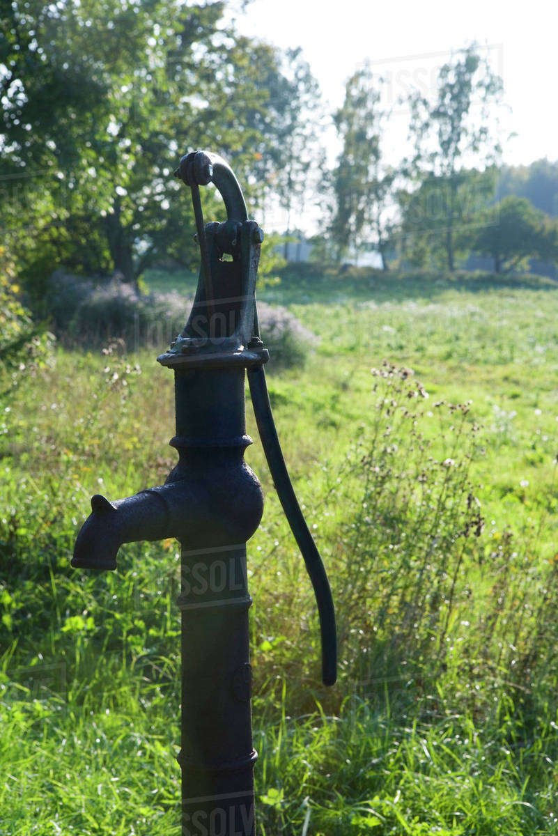 Old-fashioned water pump in sunny meadow - Stock Photo - Dissolve