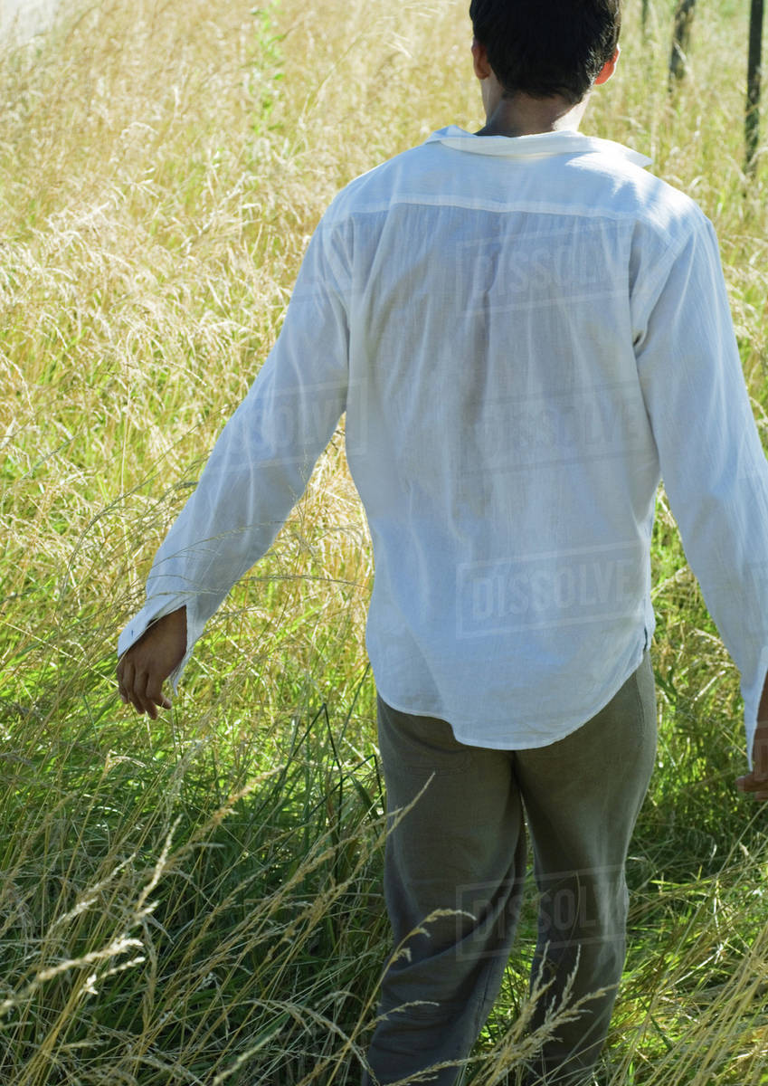 Man walking through field, rear view - Royalty-free Stock Photo | Dissolve