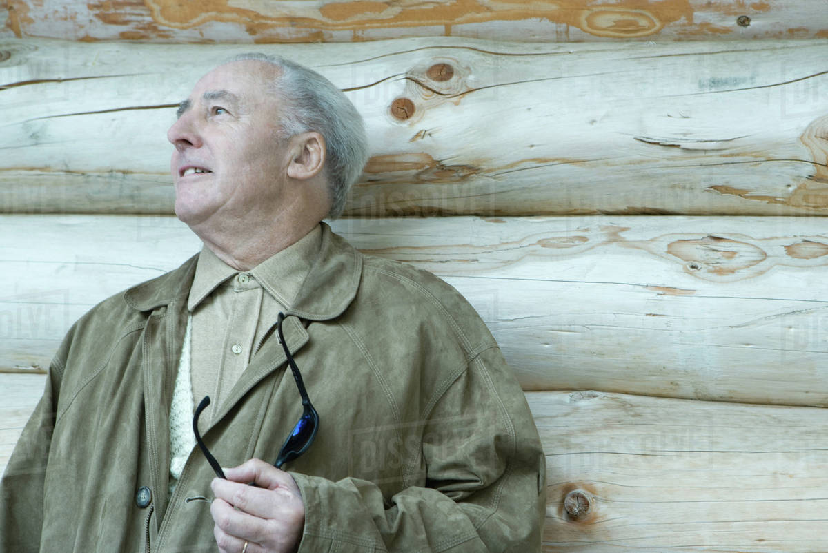 Senior man standing next to log cabin - Royalty-free Stock Photo | Dissolve