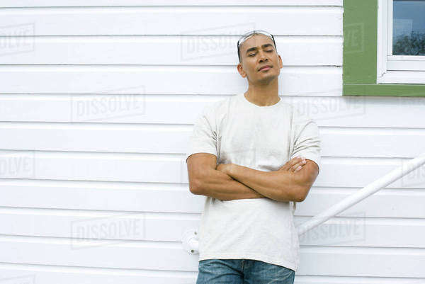 Man leaning against house with arms folded - Royalty-free Stock Photo ...