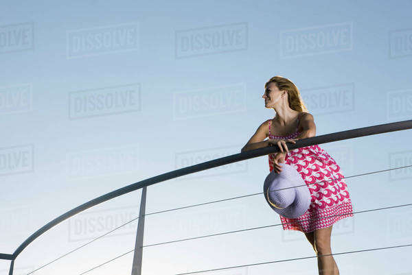 Woman leaning against balcony railing, looking at view - Royalty-free ...