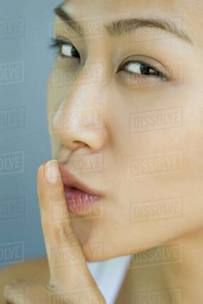 Woman holding finger against lips, portrait - Royalty-free Stock Photo ...