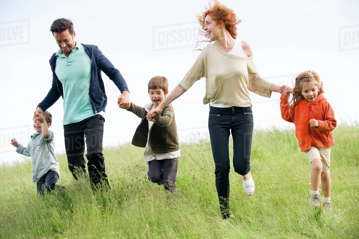 Family running together in field - Royalty-free Stock Photo | Dissolve