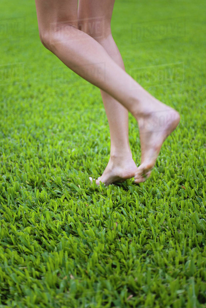 Barefoot woman walking on grass, low section - Stock Photo - Dissolve