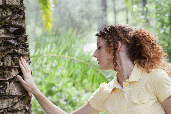 Young woman touching tree trunk - Royalty-free Stock Photo | Dissolve
