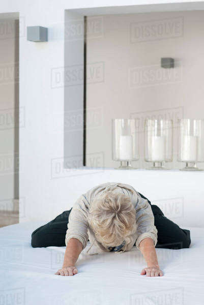 Woman kneeling on bed, leaning forward - Royalty-free Stock Photo ...