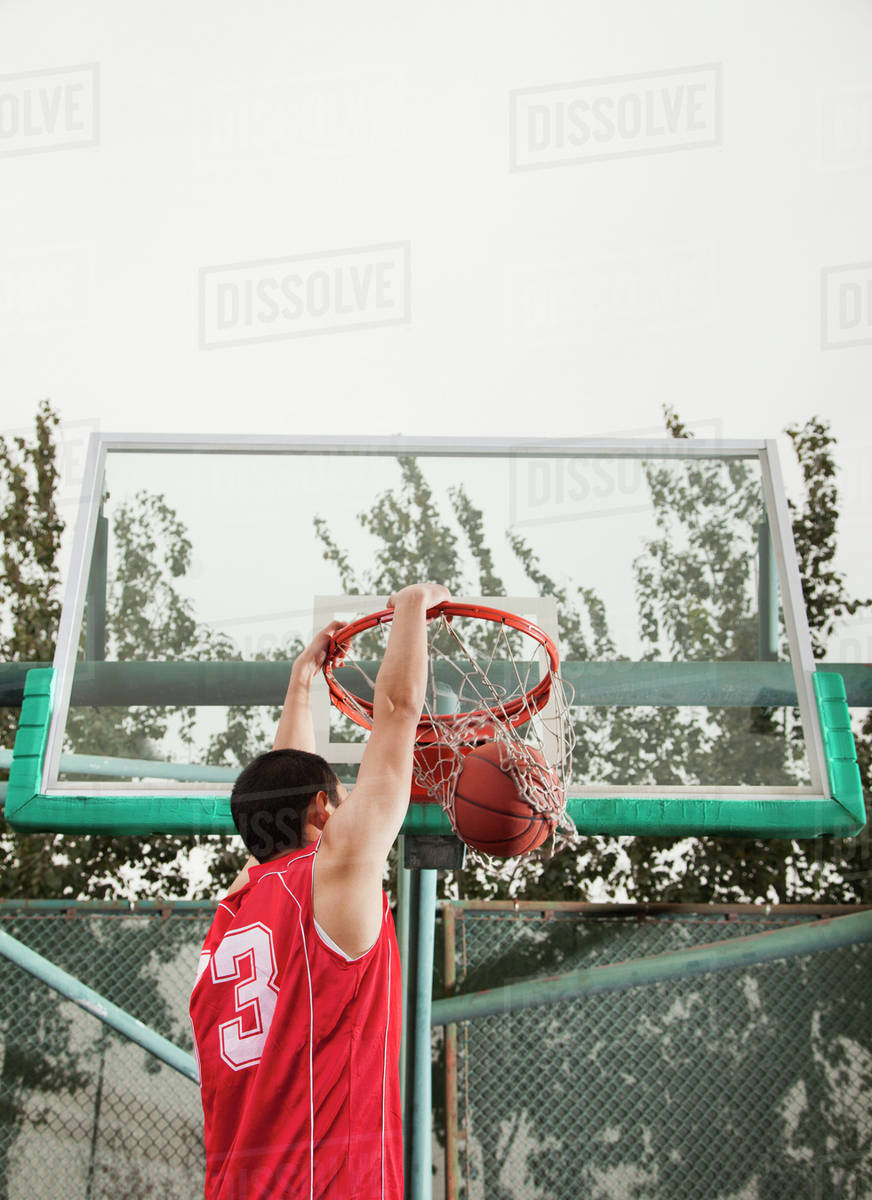 Slam dunk by young man - Stock Photo - Dissolve