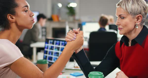 Company leader beating her employee at arm-wrestling. Black female ...