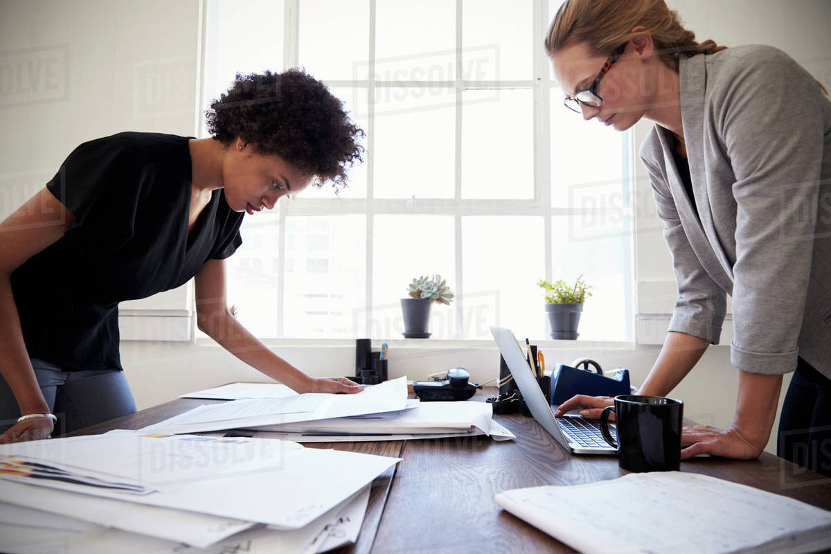 Two women work at opposite sides of an office desk, close up - Royalty ...