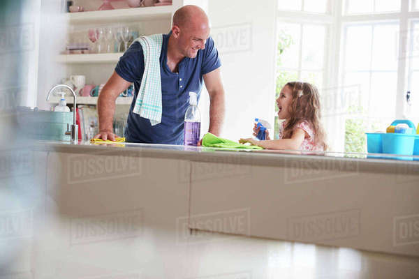 Dad and daughter cleaning the kitchen, looking at each other - Royalty ...