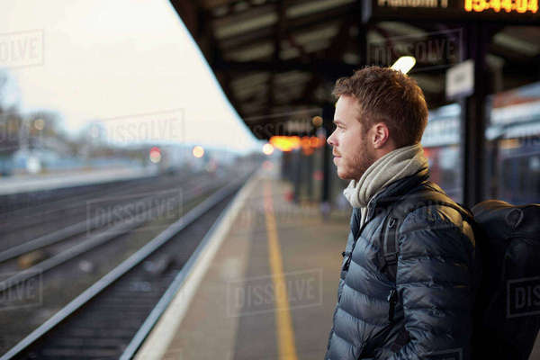 Man standing on railway platform waiting for train to arrive - Stock ...