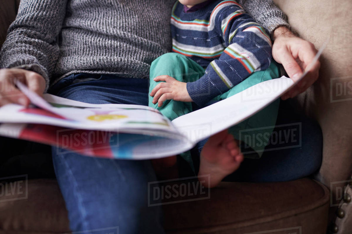 Father sitting in chair at home reading story to son - Royalty-free ...