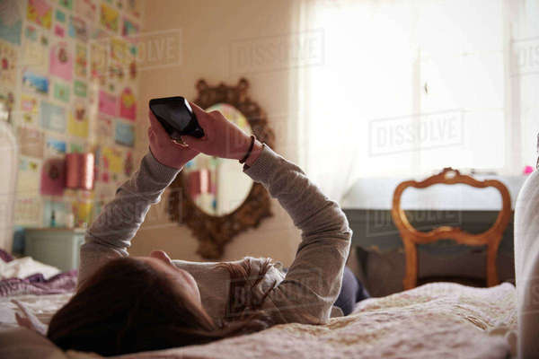 Teenage girl using mobile phone in bedroom at home - Royalty-free Stock ...
