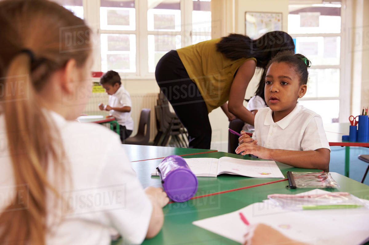 Pupils working at desks in elementary school classroom - Royalty-free ...