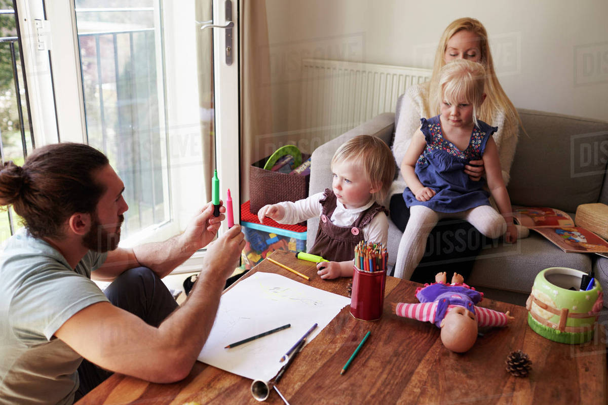 Family sitting at table and drawing pictures together - Royalty-free ...