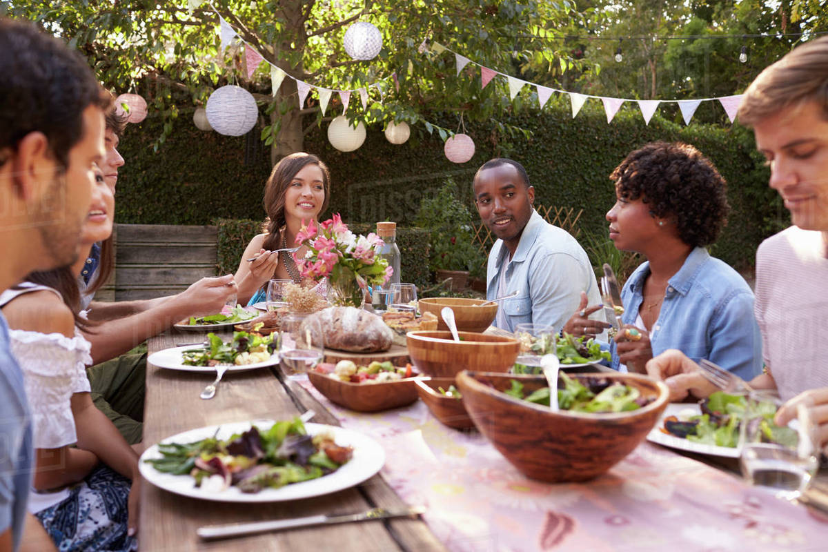 Friends Eating And Drinking Around Table At Outdoor Party - Royalty ...