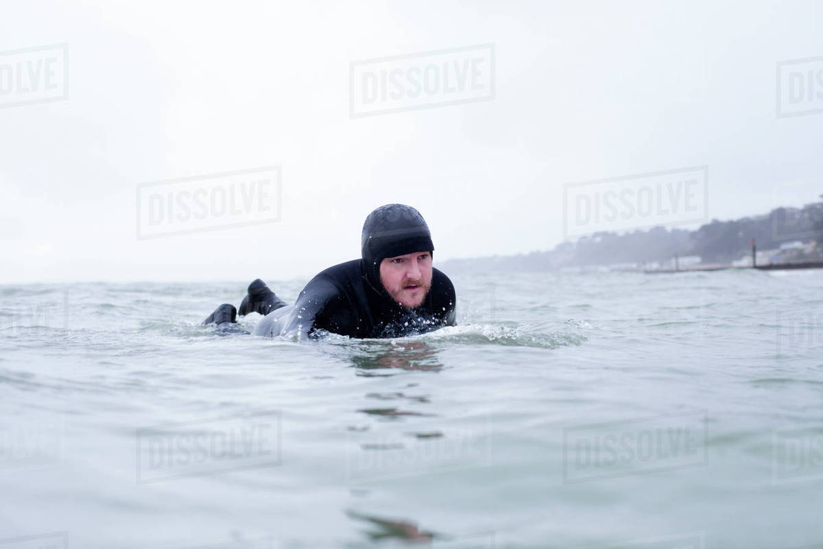 Surfer wearing wetsuit floating with board in wintery sea - Stock Photo ...