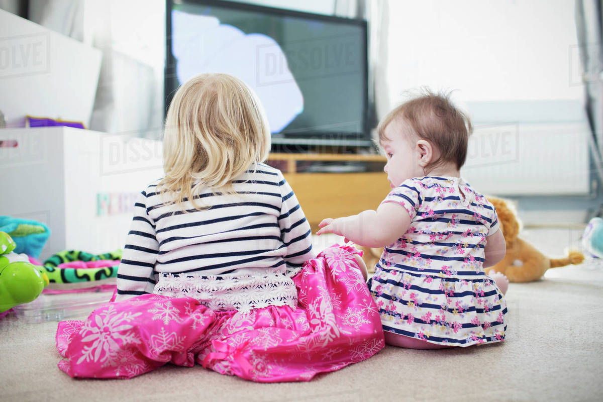 Young girl with younger sister watching tv together - Royalty-free ...