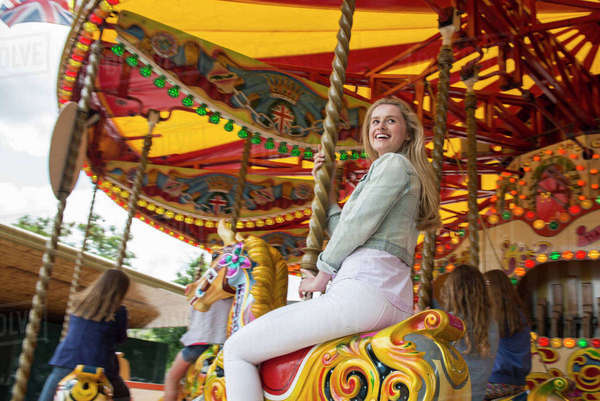 An attractive blond girl riding a carousel on the South Bank in London ...