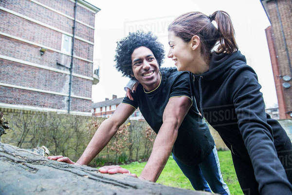 A young couple limbering up together ready for a jog in Southwark Park ...