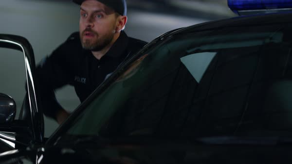 Policeman standing behind doors of police car. Cop aiming gun at police ...
