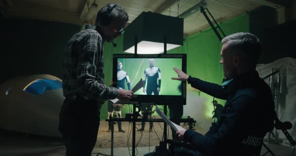 Medium shot of a director giving instructions to film crew member while ...