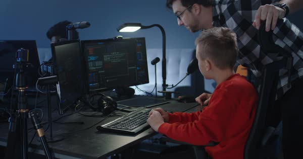 Medium shot of a child programmer getting instructions from his adult ...