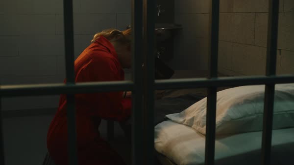 Female prisoner prays to God in prison cell holding Bible - 4K Royalty ...