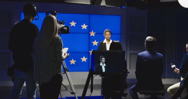 Female news anchor reading the news in front of a European flag with a ...