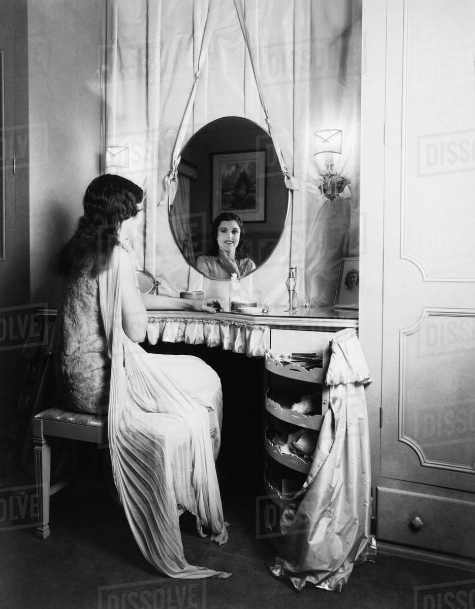 Woman looking in mirror at dressing table - Royalty-free Stock Photo ...