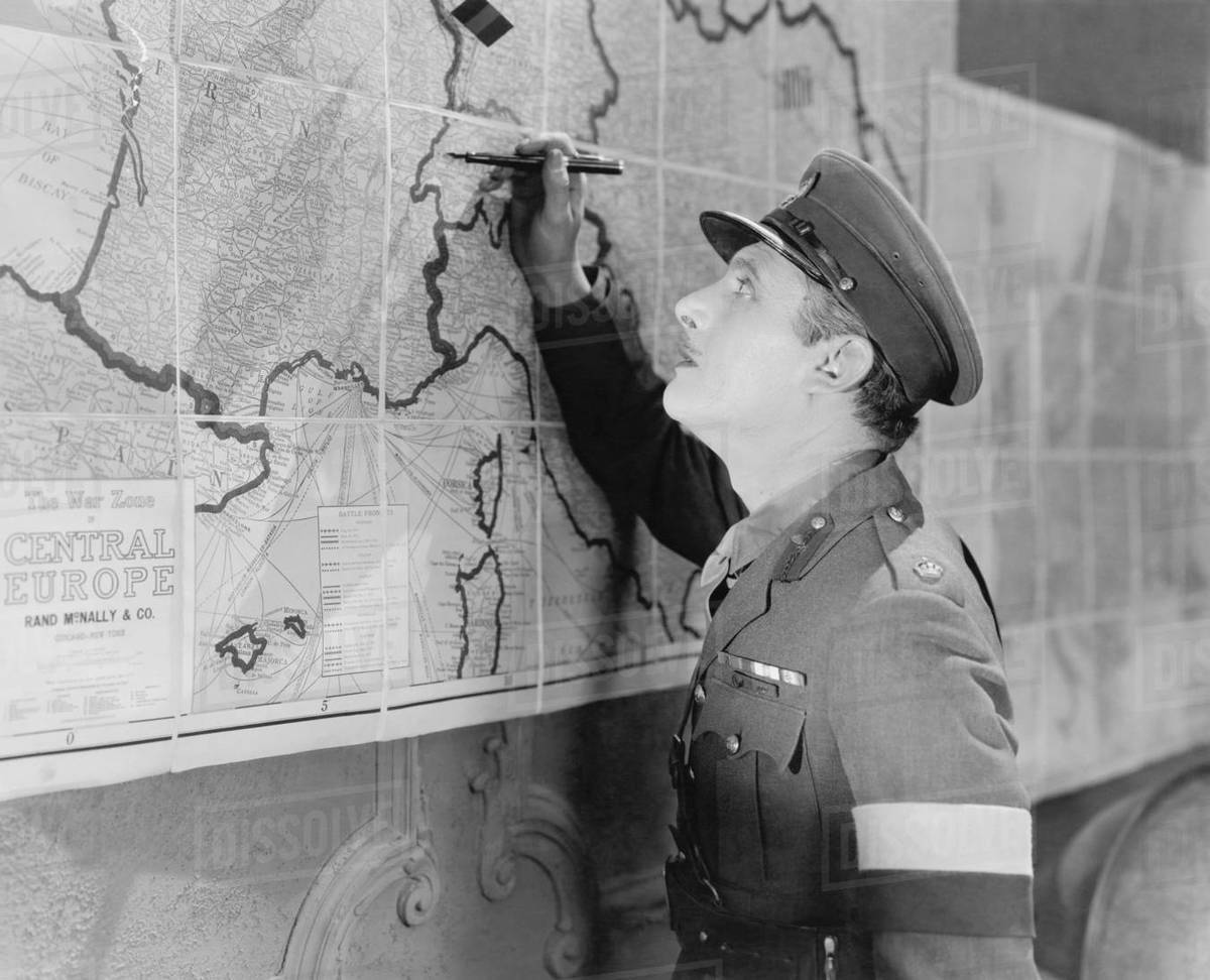 Soldier looking at a map marking it with a pen - Stock Photo - Dissolve