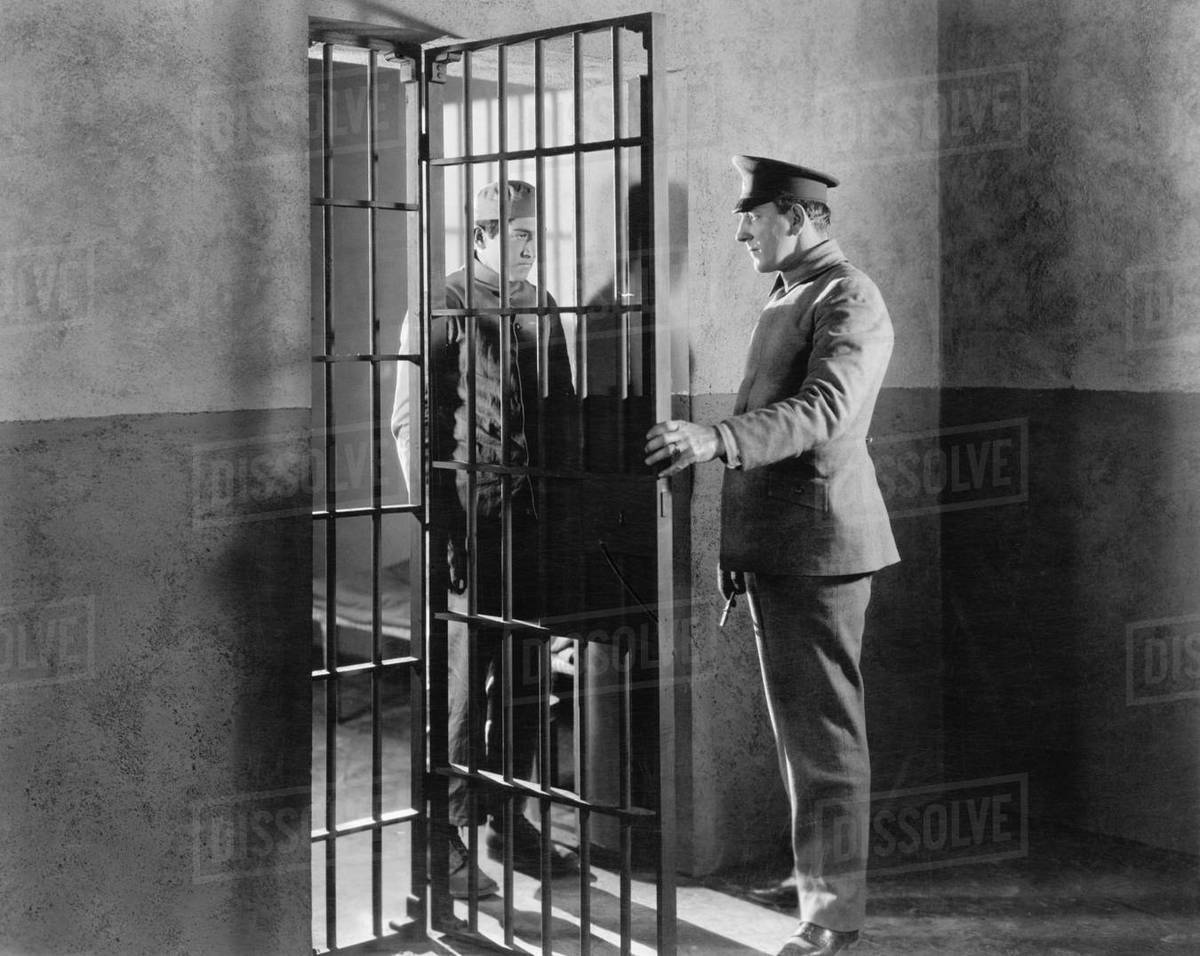 Policeman and prisoner in a jail cell - Royalty-free Stock Photo | Dissolve