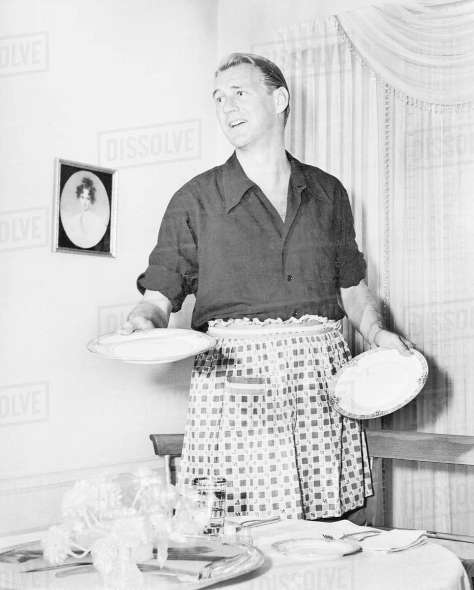 Man in an apron setting the table - Royalty-free Stock Photo | Dissolve