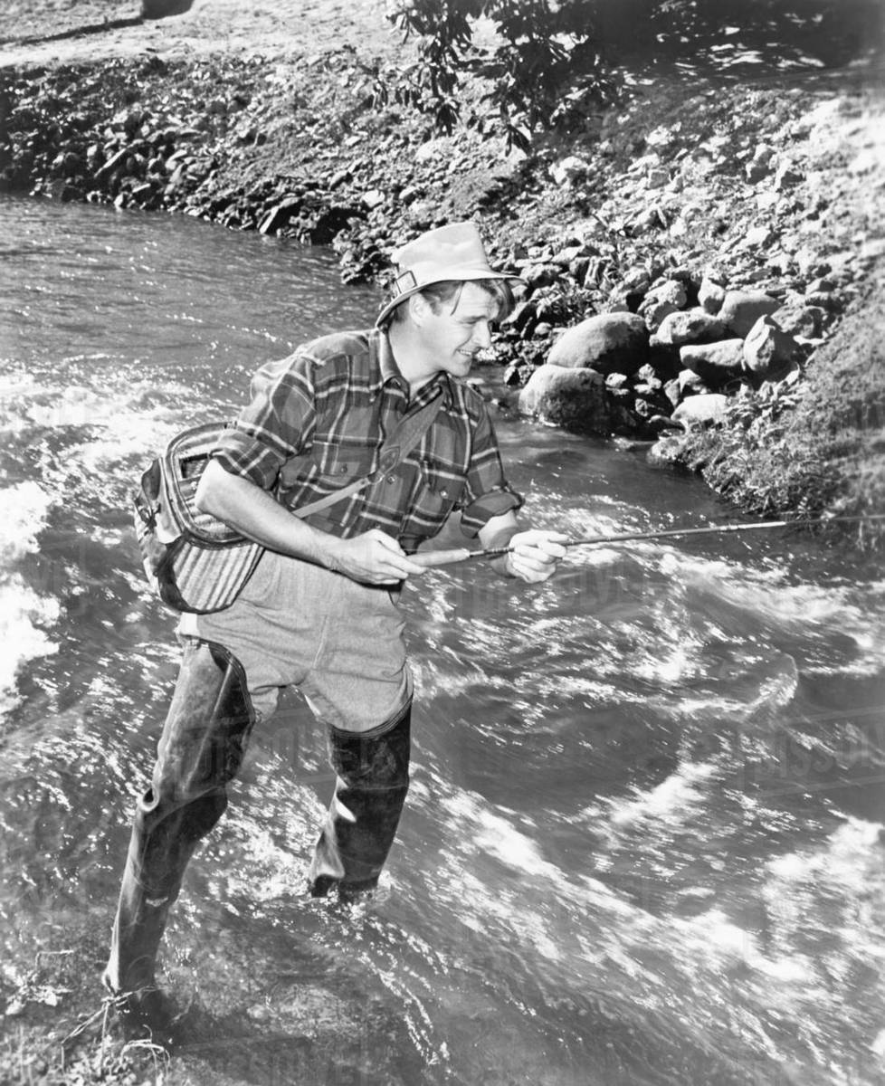 Man standing in a stream of water fishing - Stock Photo - Dissolve