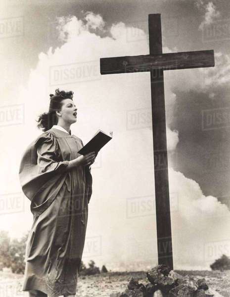 Woman singing hymns by a large wooden cross on a hill - Royalty-free ...