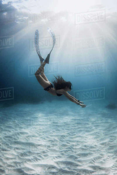 Beauty freediver woman swims underwater. Freediving over sandy sea ...