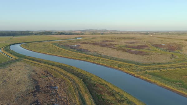 Forward flight towards and over Tarwin river and green fields at sunset ...